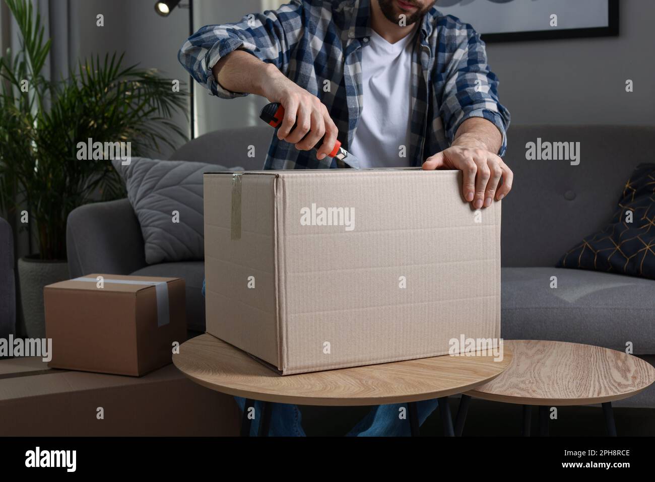 Man using utility knife to open parcel at home, closeup Stock Photo - Alamy