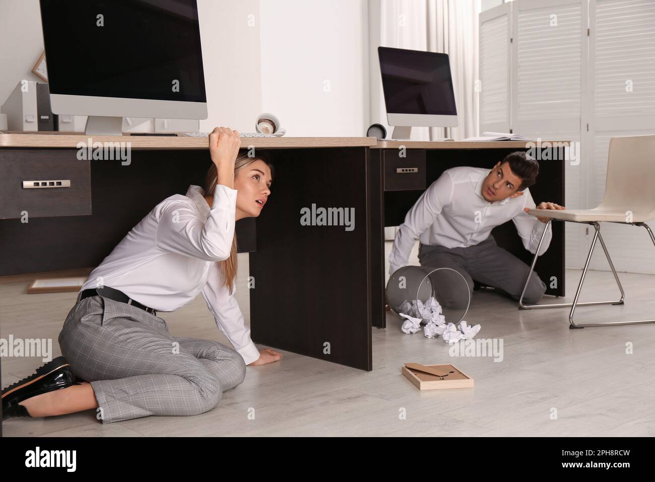 Scared employees hiding under office desks during earthquake Stock ...