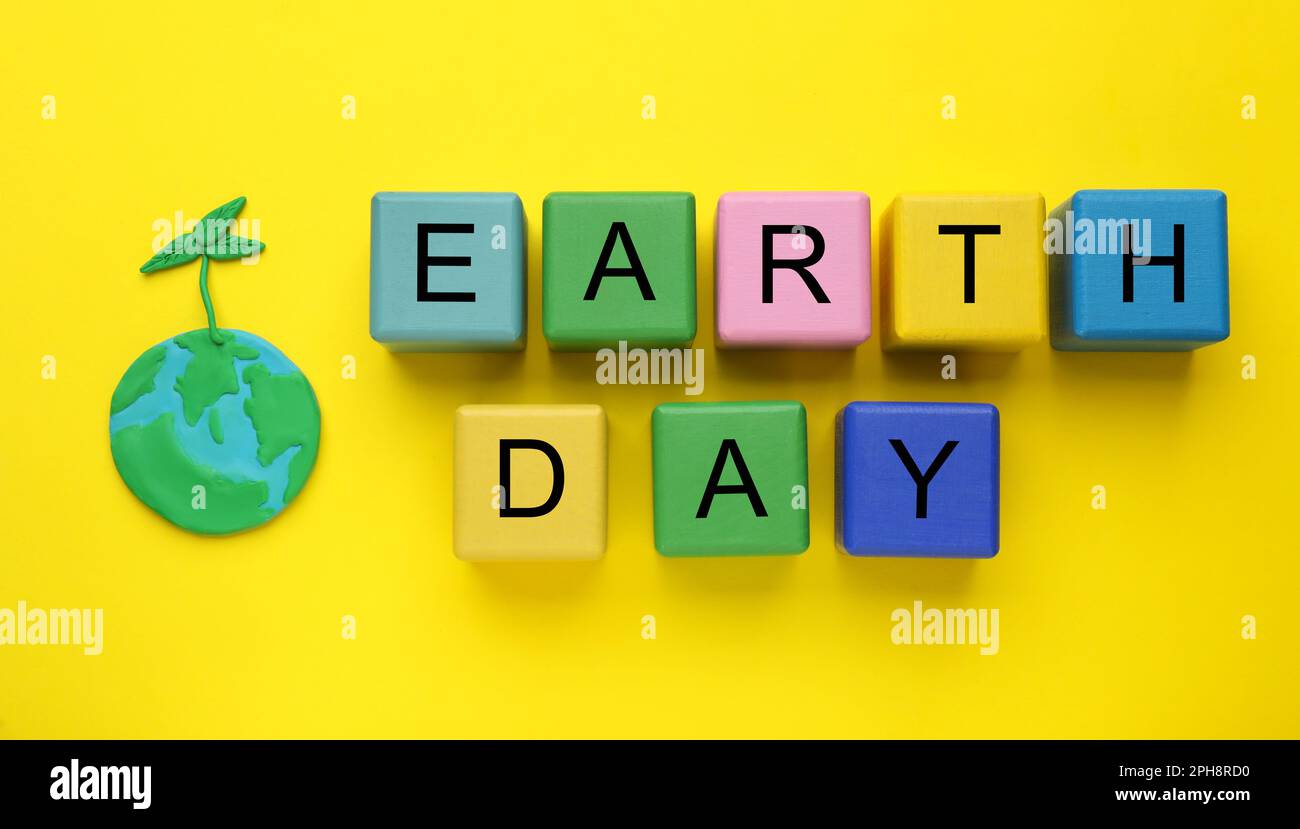Phrase Earth Day made with cubes and model of planet on yellow ...