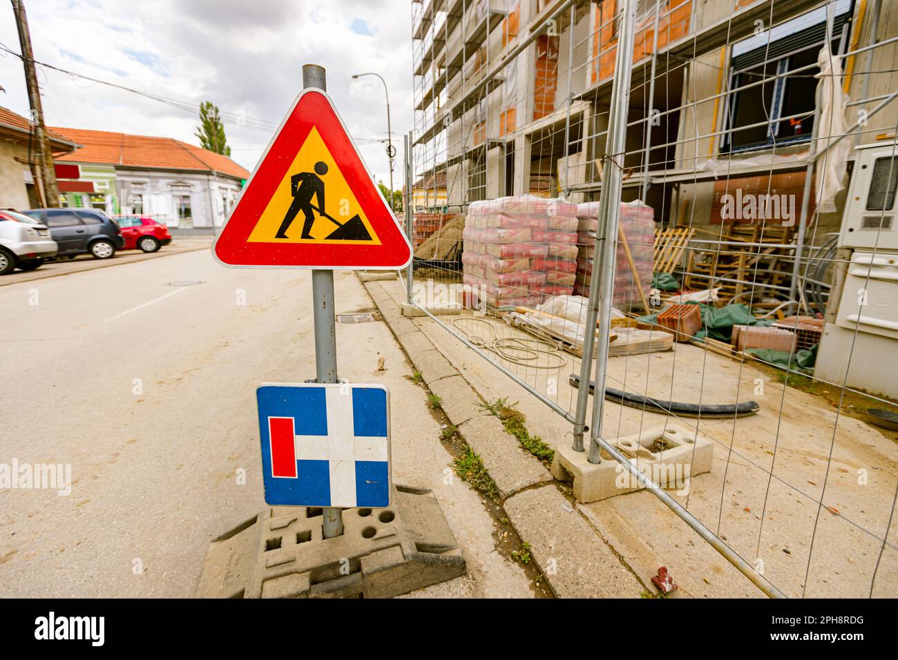 Red triangle traffic sign for road works and blue signpost for indicate ...