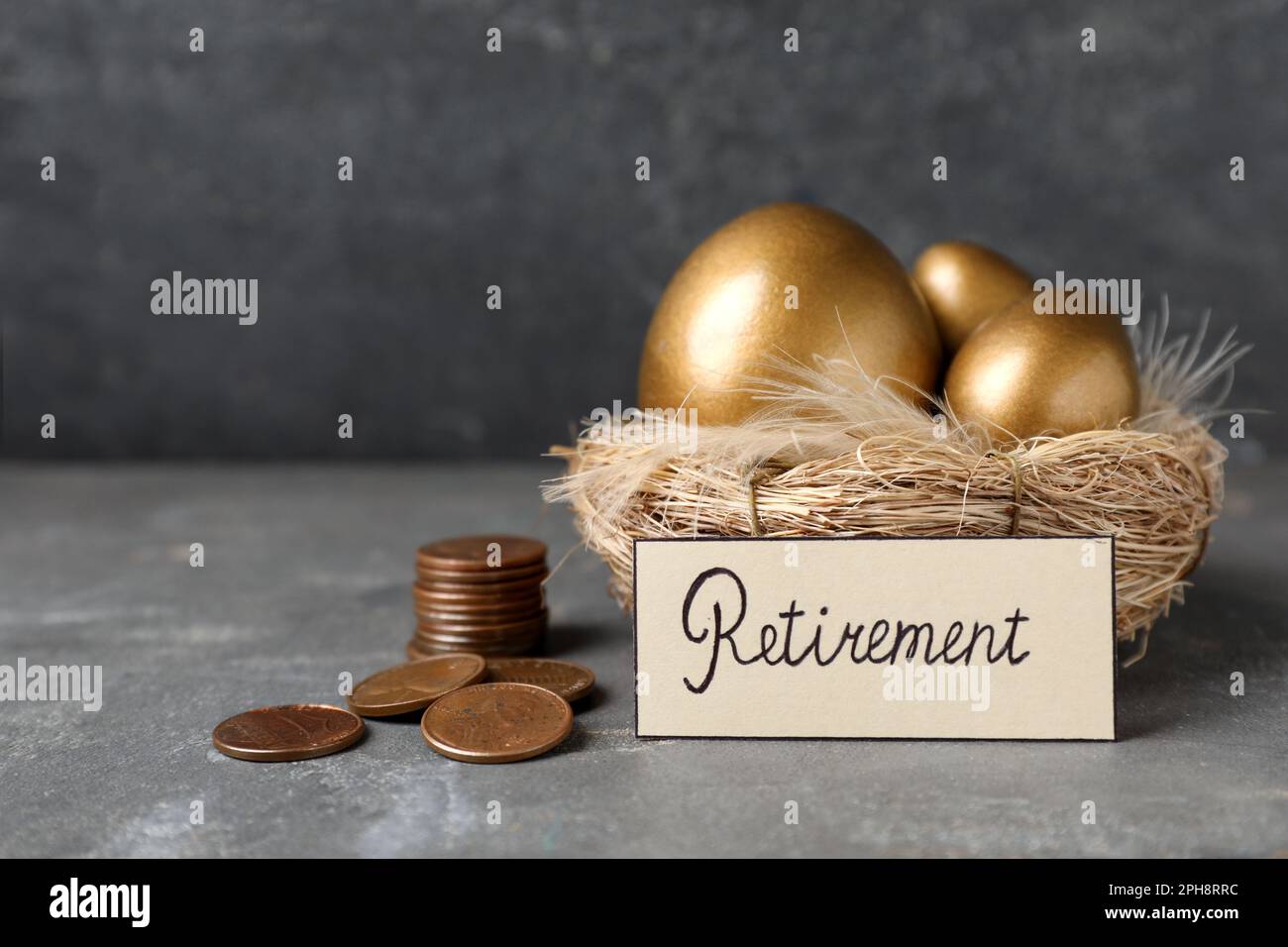Many golden eggs, coins and card with word Retirement on grey table ...