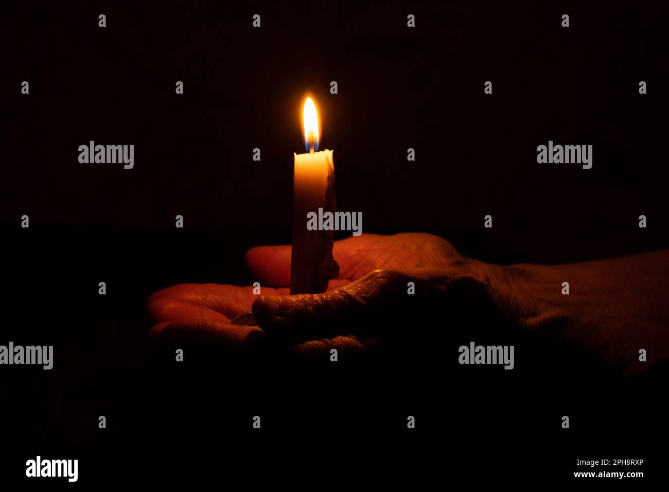 old woman's hands and candle flame in the dark, candle light, mourning ...