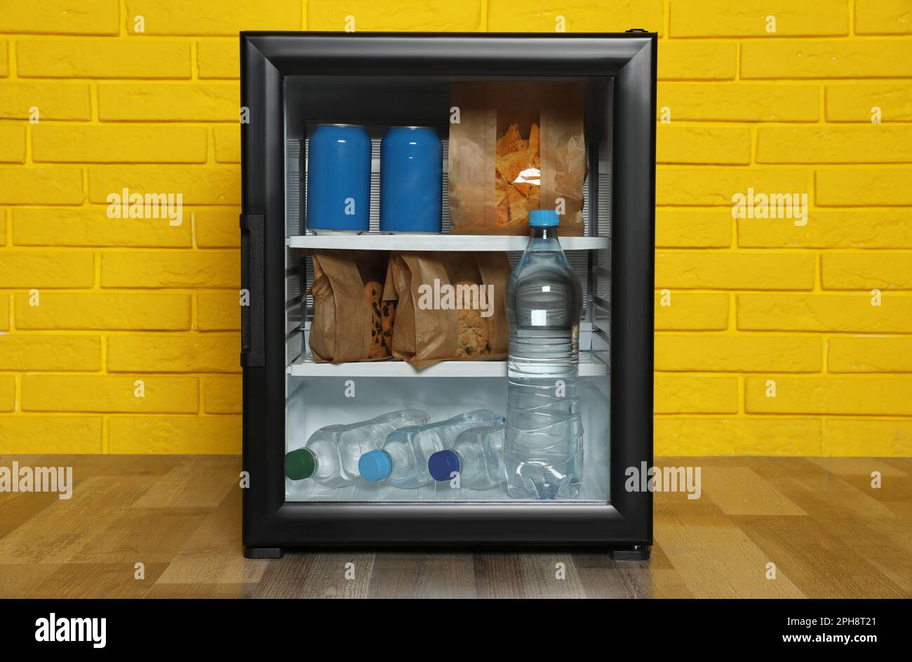 Mini bar filled with food and drinks near yellow brick wall indoors ...