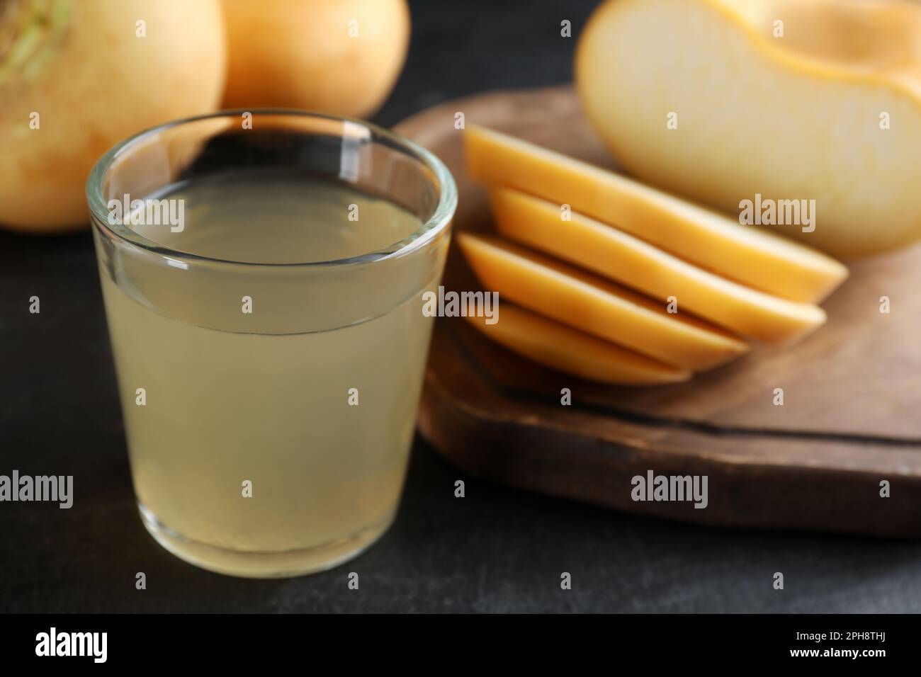 Glass of fresh natural turnip juice, cut and whole roots on black table ...