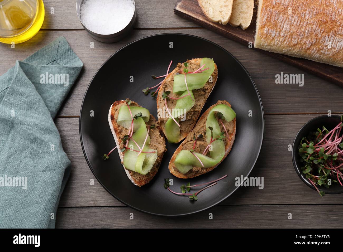 Slices of bread with delicious pate, cucumber and microgreens on wooden ...