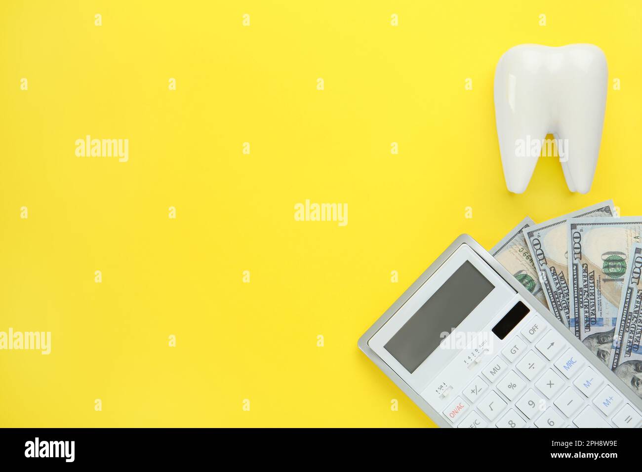 Ceramic model of tooth, dollar banknotes and calculator on yellow ...
