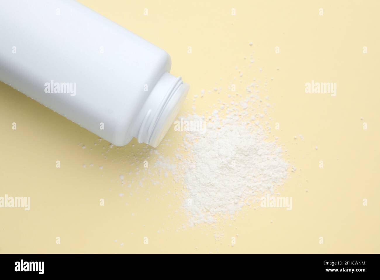 Bottle and scattered dusting powder on beige background, top view. Baby ...
