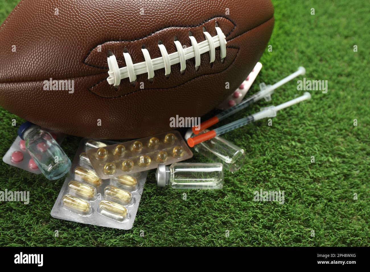 American football ball and different drugs on green grass, closeup ...