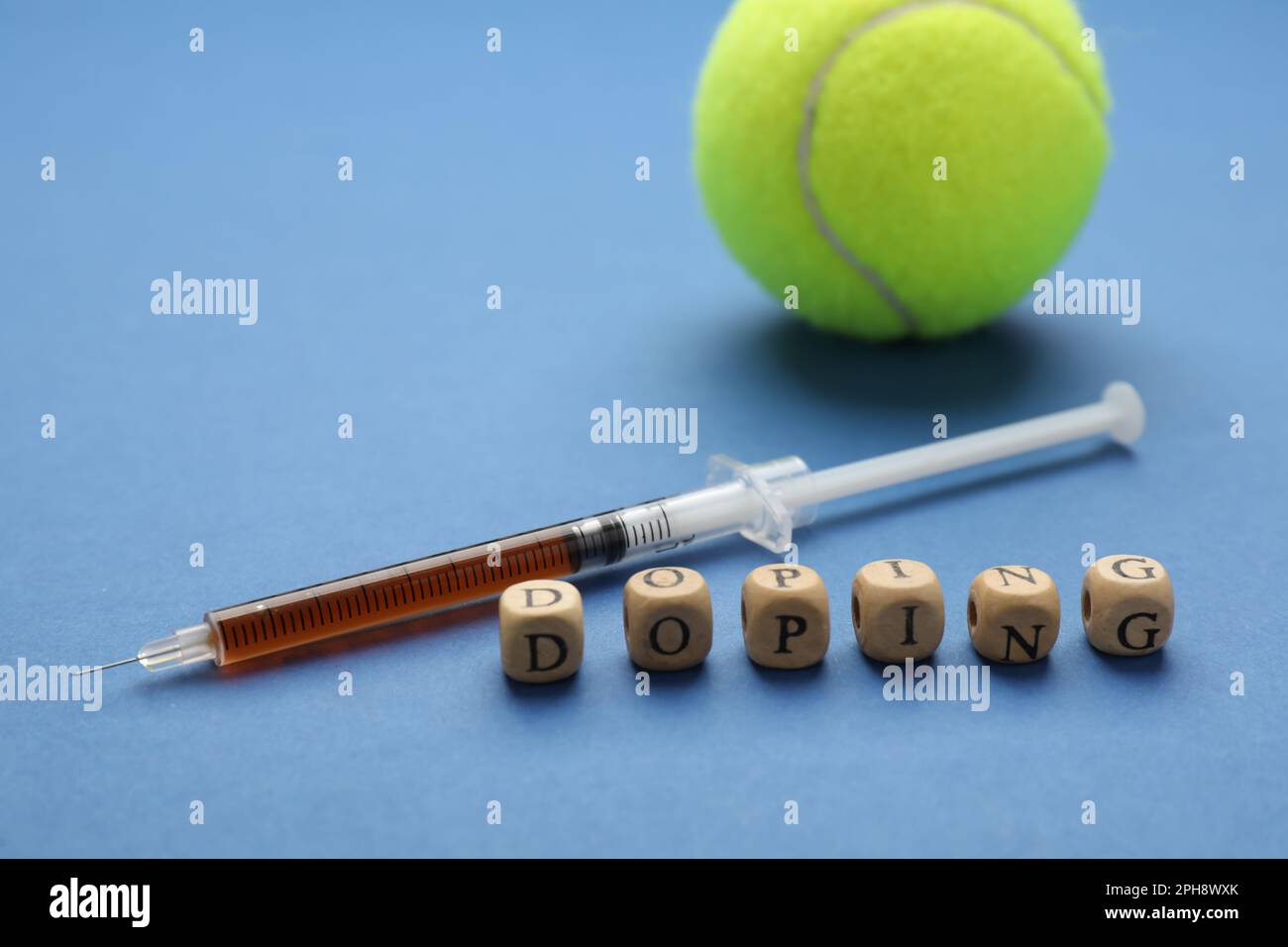 Wooden cubes with word Doping, syringe and tennis ball on blue ...