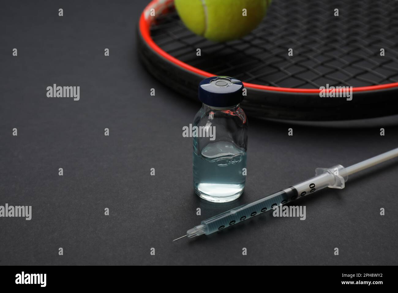 Vial and syringe near tennis racket with ball on black background ...