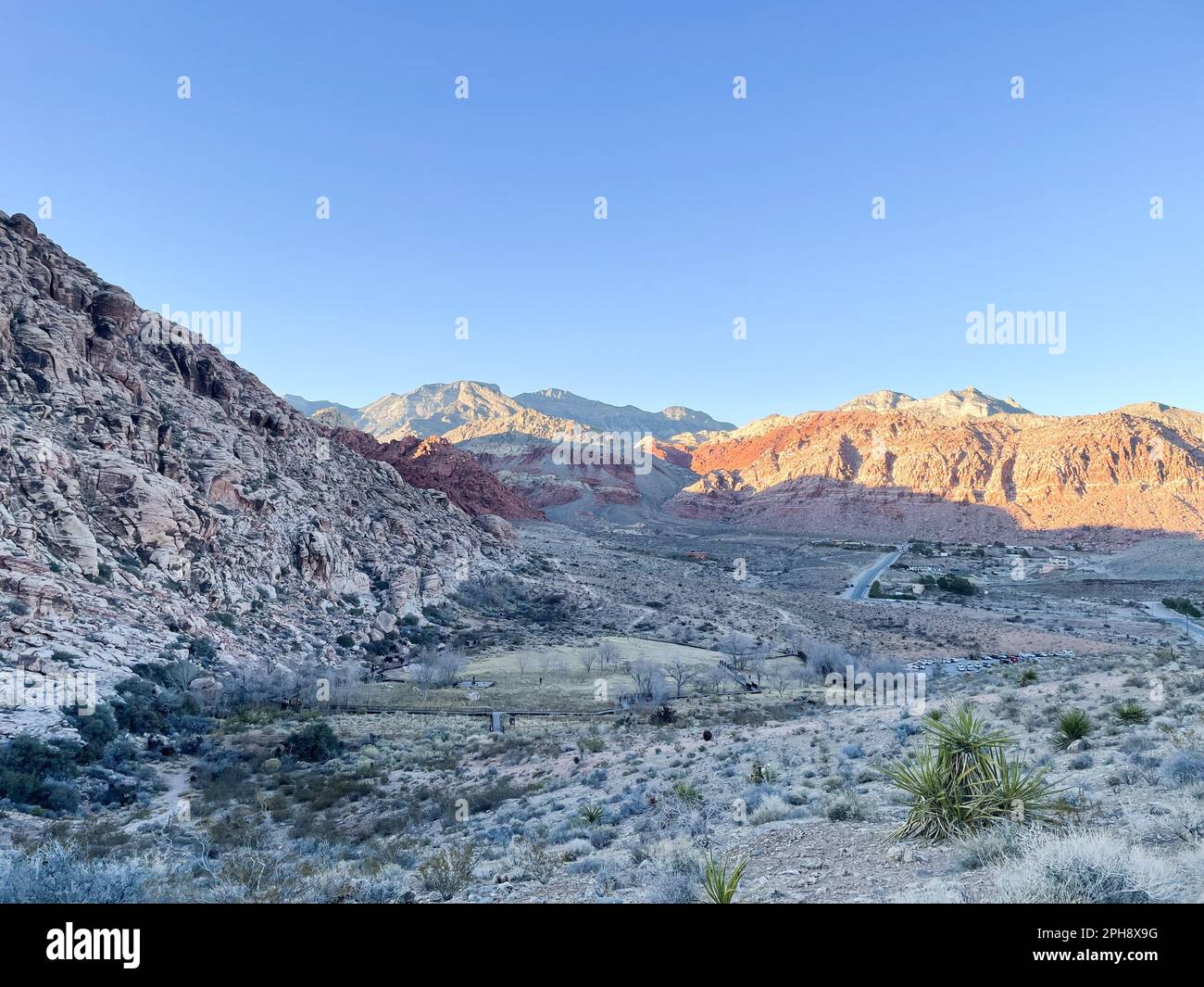 An isolated, sun-drenched mountain road stretches across a barren ...