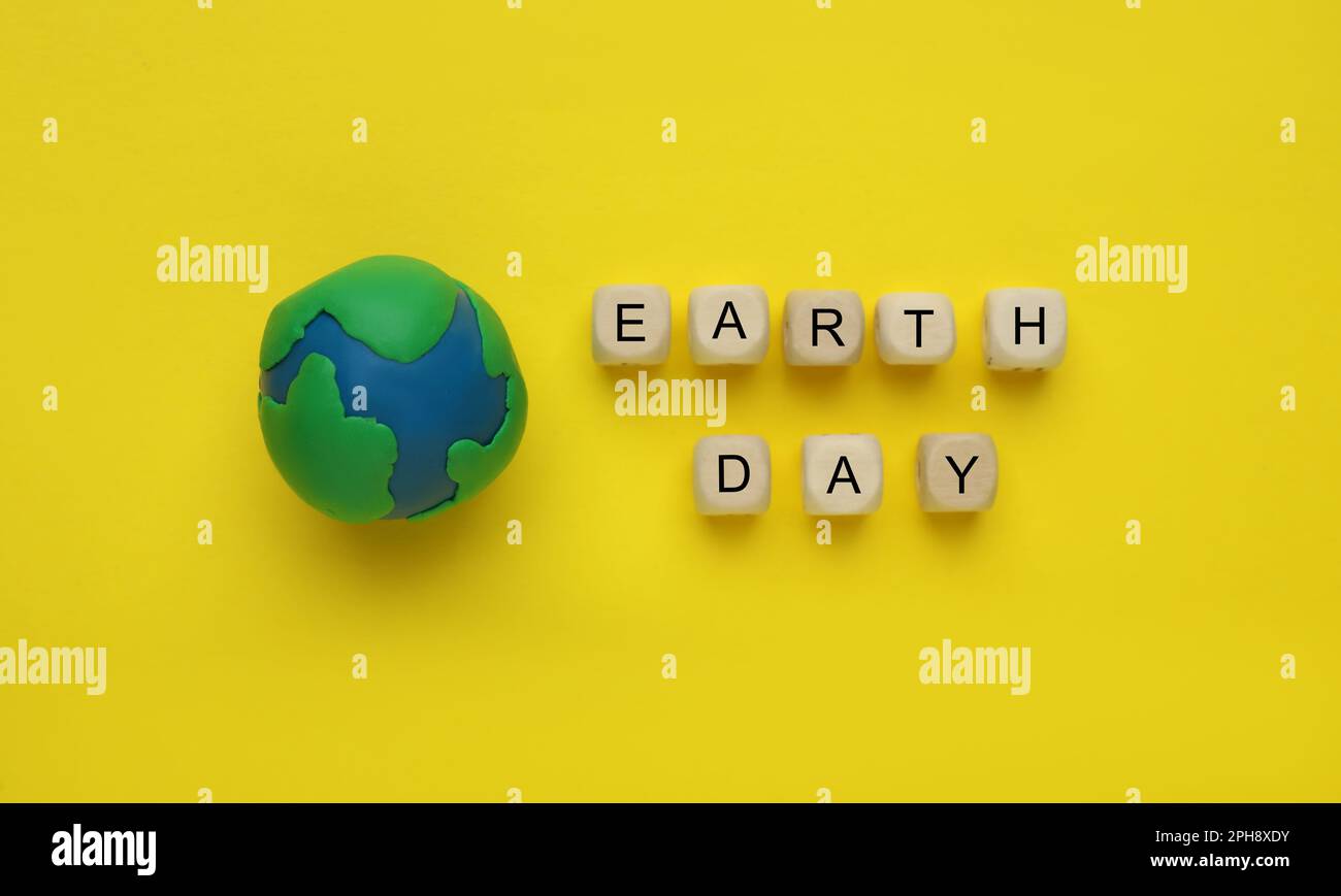 Plasticine model of planet and phrase Earth Day on yellow background ...