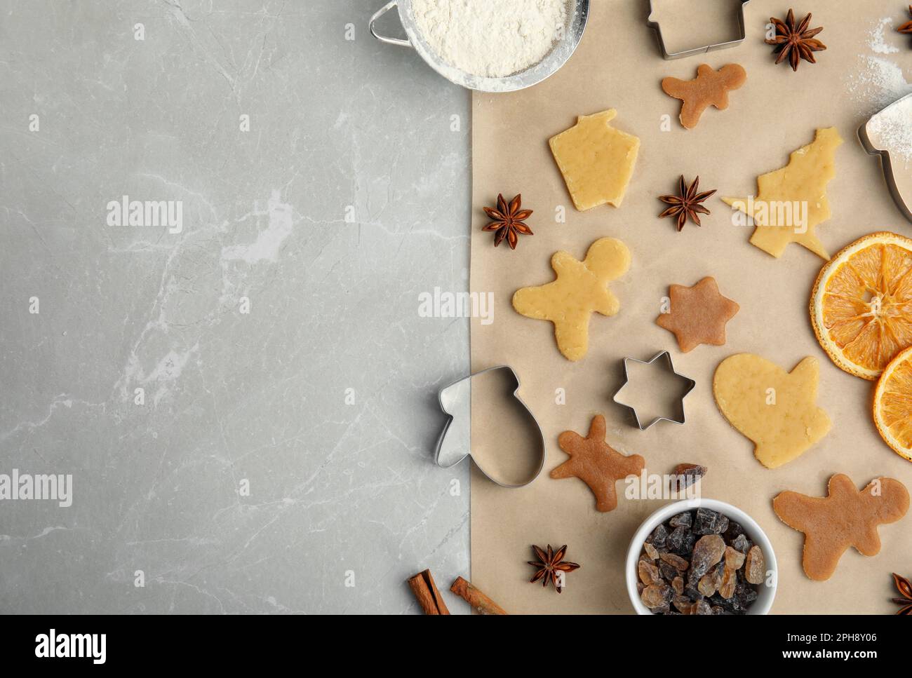 Flat lay composition with unbaked cookies and cutters on light grey ...