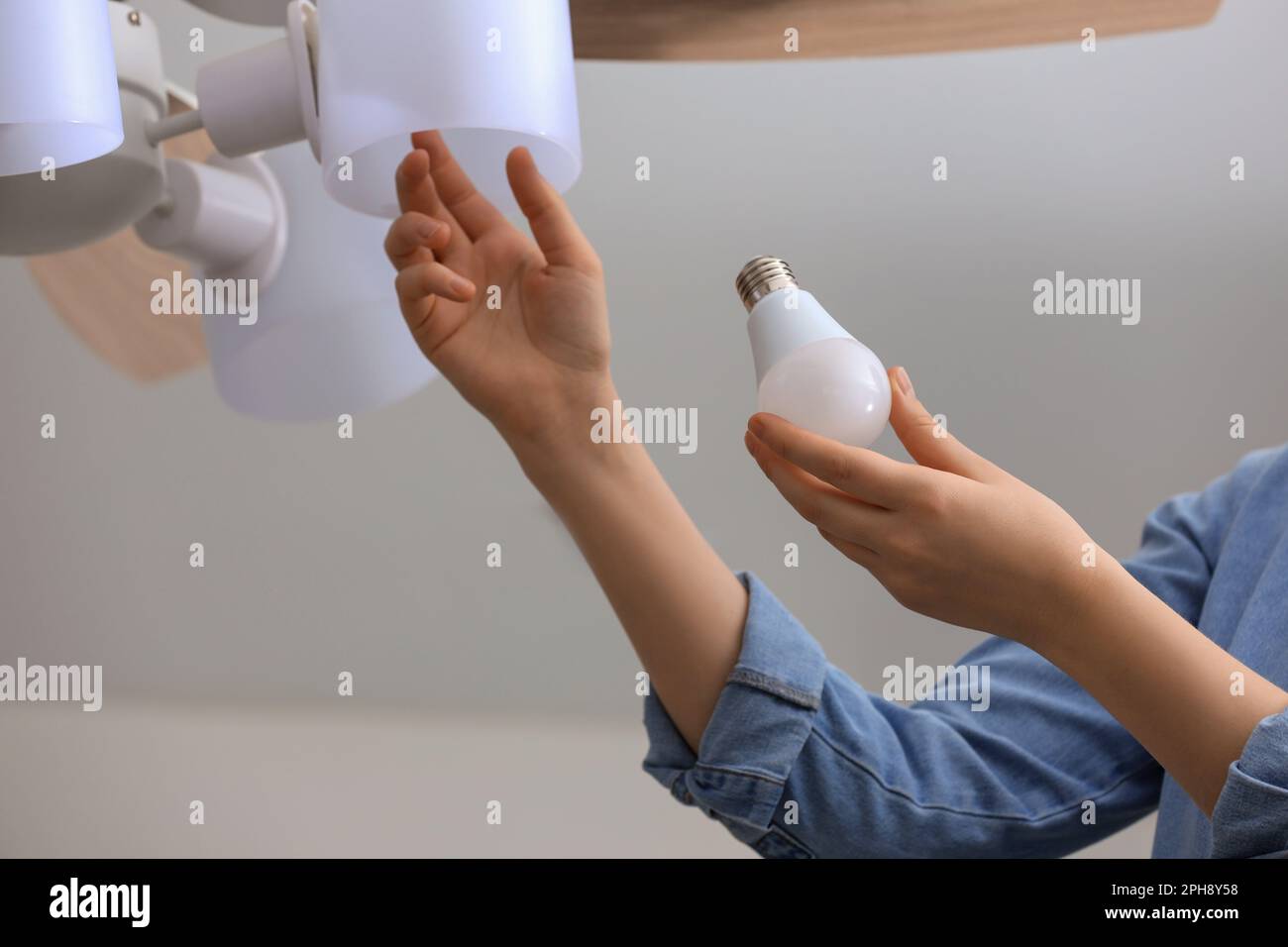Woman changing fluorescent light bulb in ceiling lamp at home, closeup ...