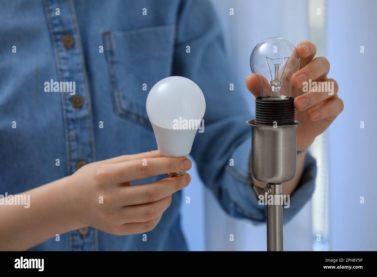 Woman changing incandescent light bulb for fluorescent one in lamp at ...
