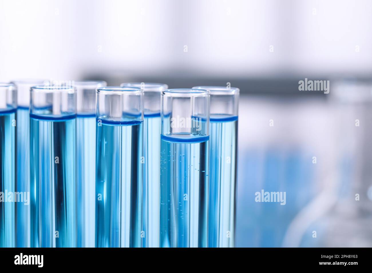 Test tubes with reagents on blurred background, closeup. Laboratory ...