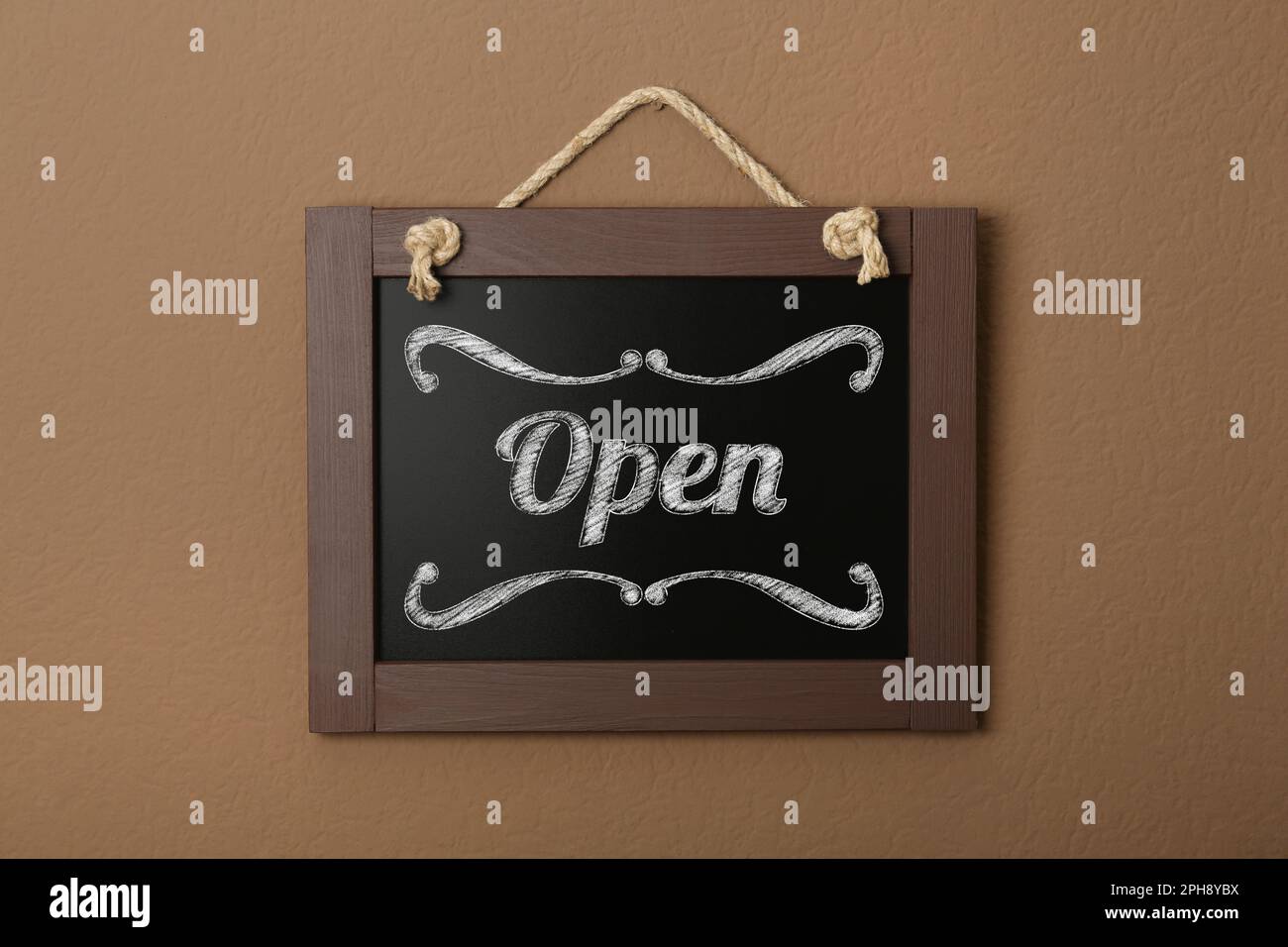 Small chalk board with word Open on brown wall Stock Photo - Alamy