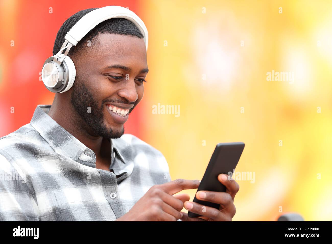 Happy black man wearing headphones listening to music on smartphone Stock Photo - Alamy