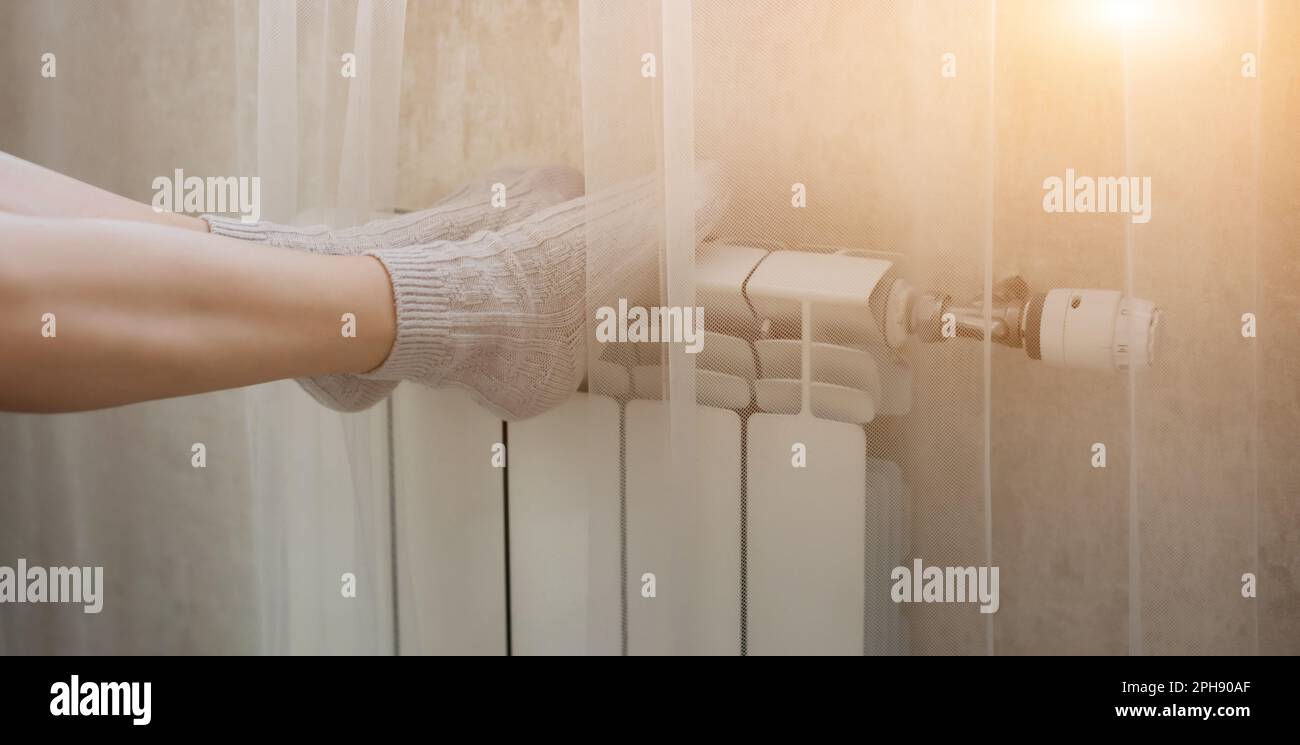 female legs in socks on warm radiator. Woman warming up her feet Stock ...