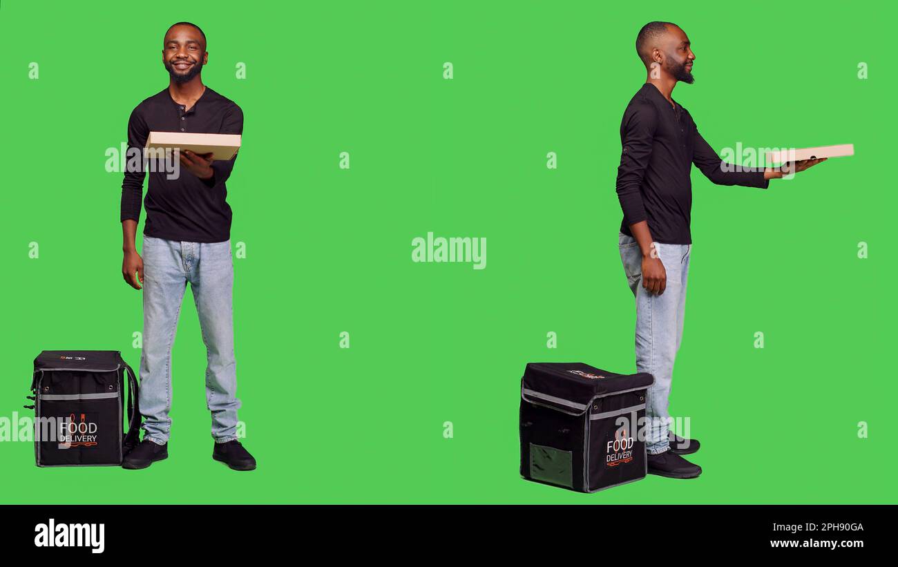 Casual young adult working as deliveryman in studio, carrying takeout ...
