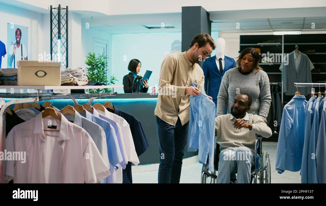 Young person with physical disability checking clothes in store ...