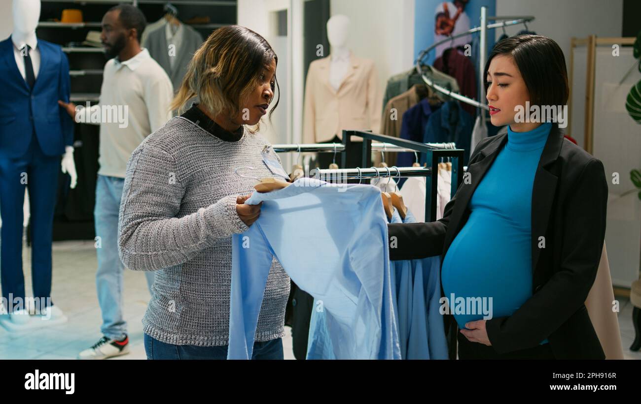 Asian woman with baby bump shopping for clothes in department store at ...