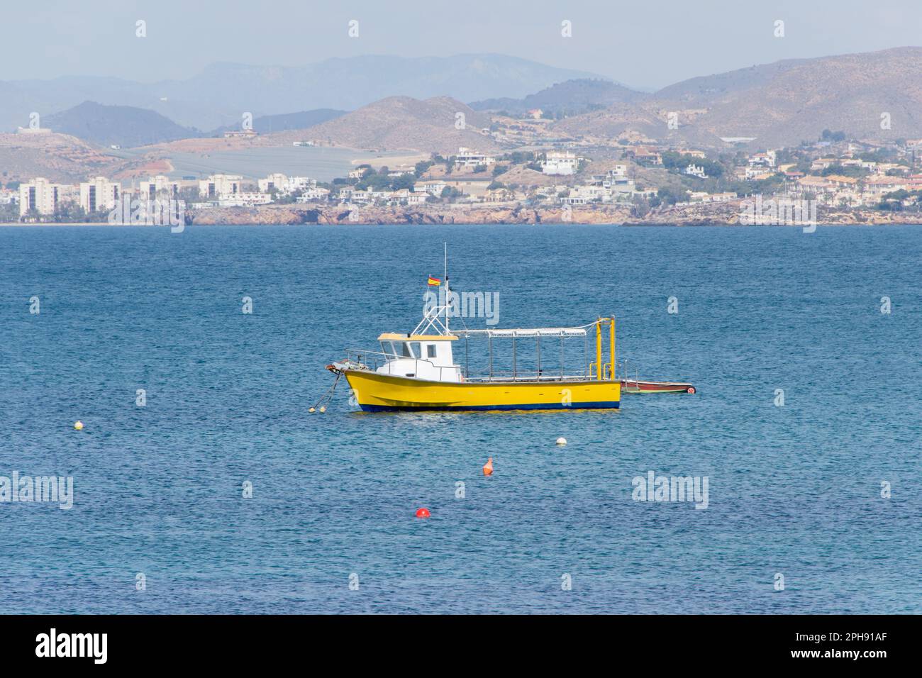 A small yellow boat with the Spanish flag sails in the Mediterranean ...