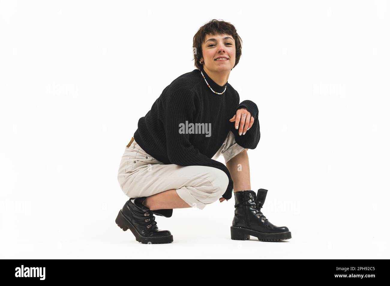 Woman crouching and bending on her knee for a model photoshoot smiling ...