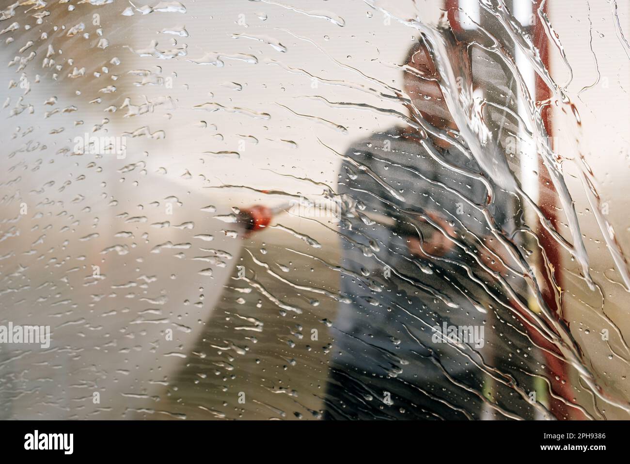 Man washing car with water gun in carwash self-service. Soap sud, wax ...