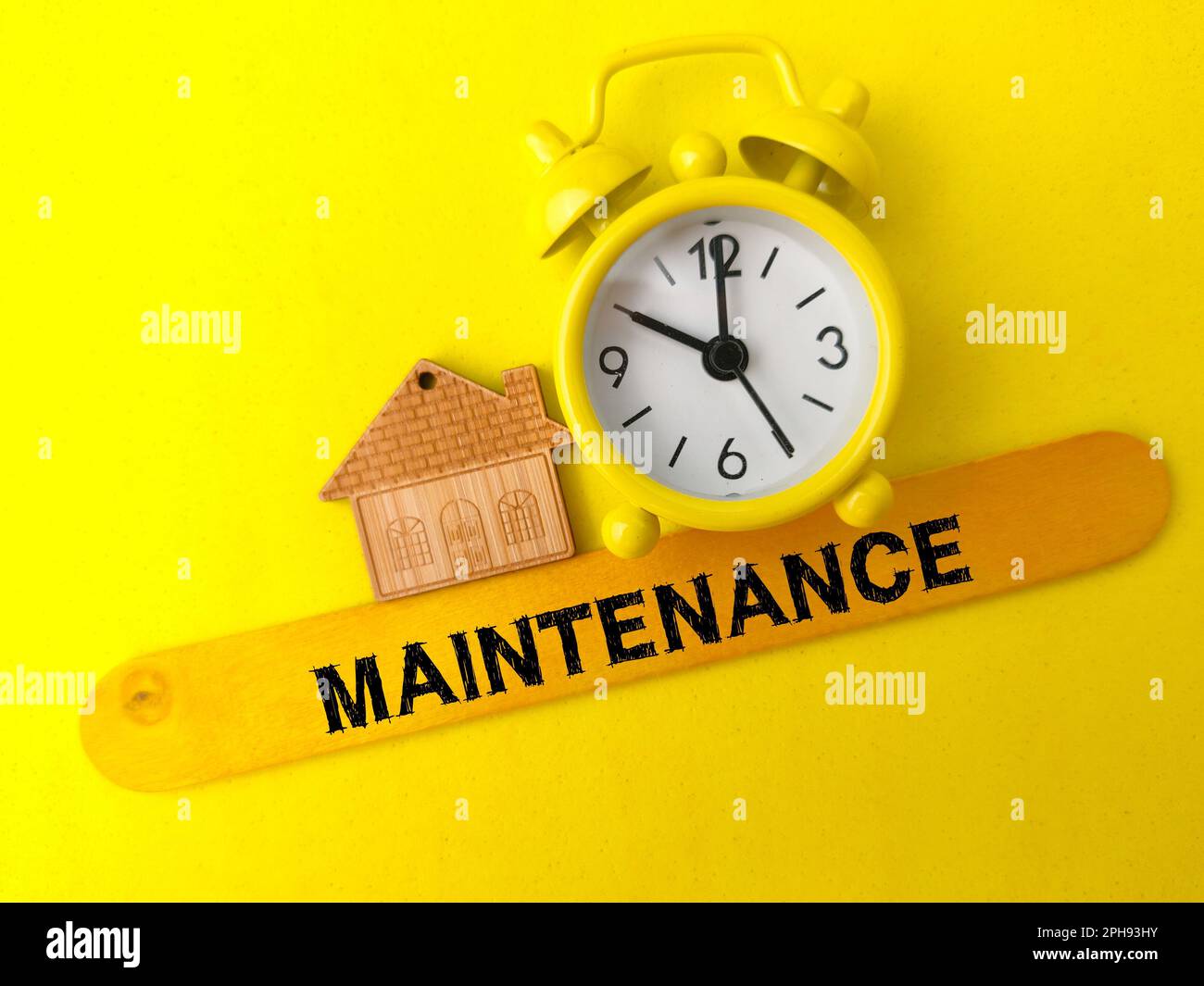 Clock and wooden house with the word MAINTENANCE on yellow background ...