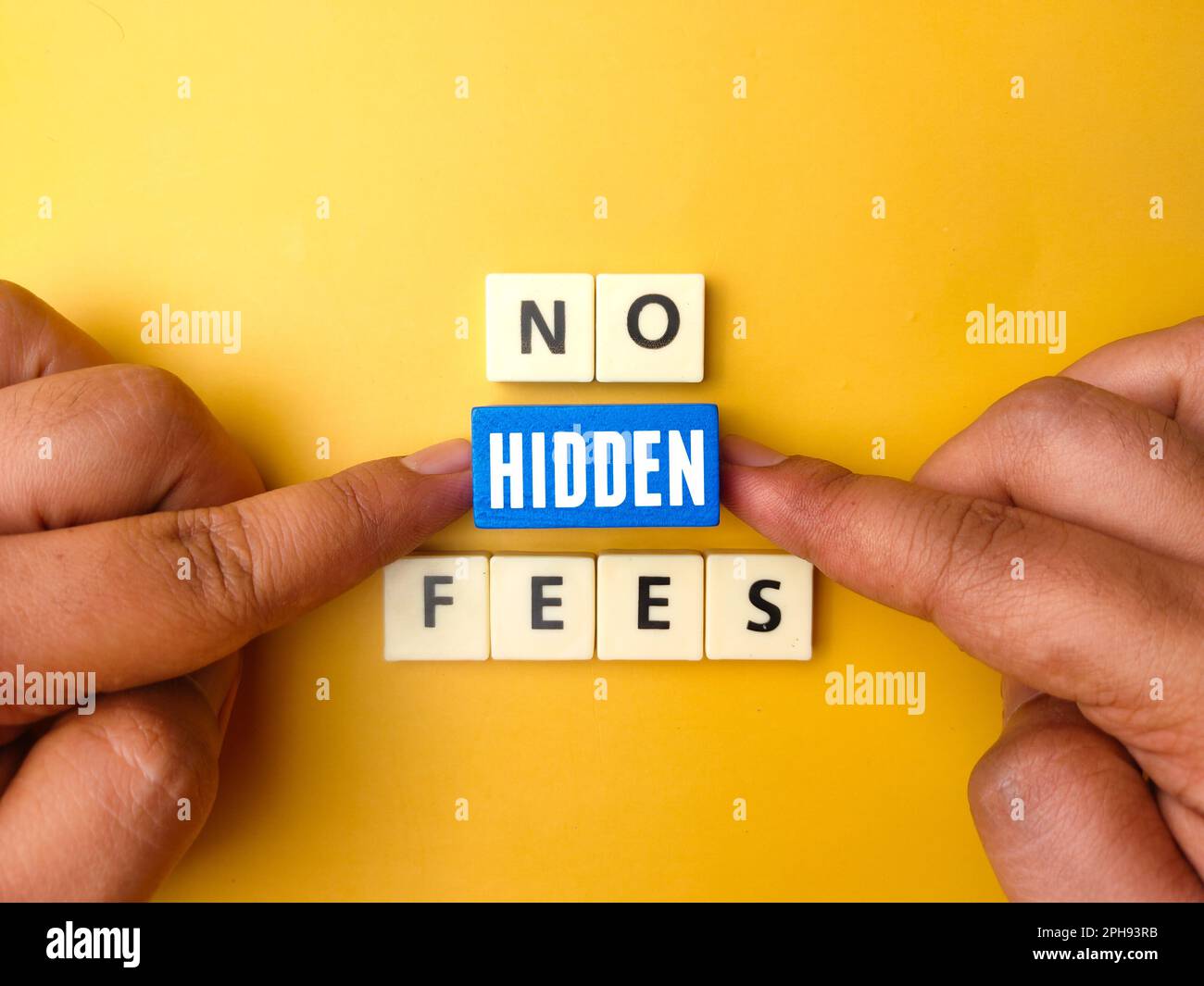 Hand holding colored cube with the word NO HIDDEN FEES on yellow ...