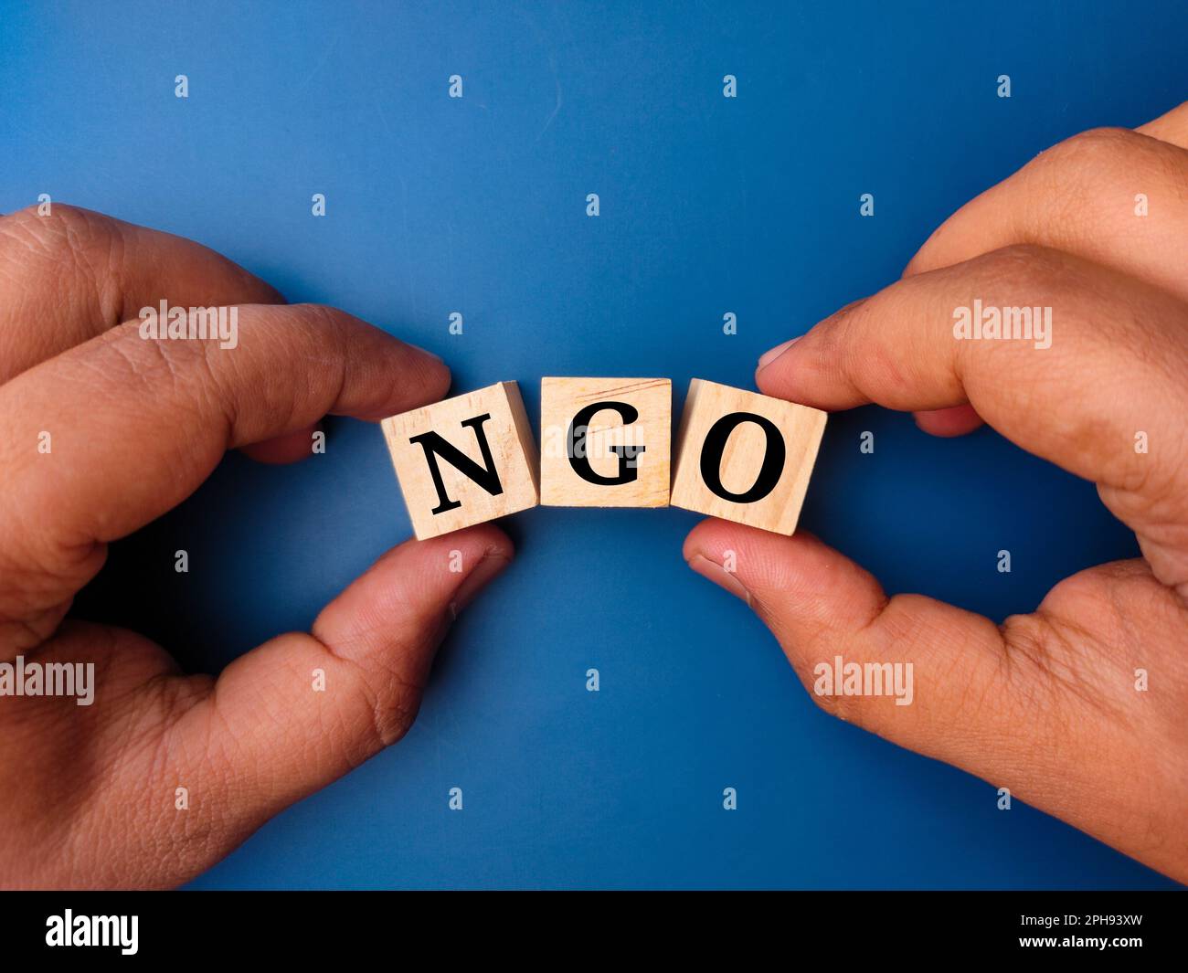 Hand holding colored cube with the word NGO on blue background Stock ...