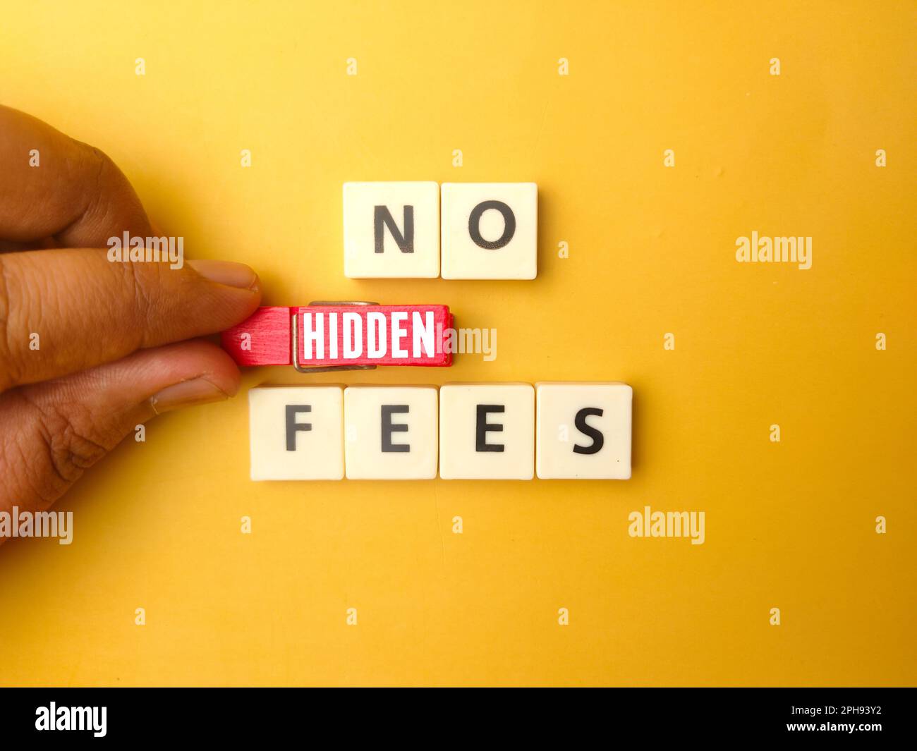 Hand holding wooden clips with the word NO HIDDEN FEES on yellow ...