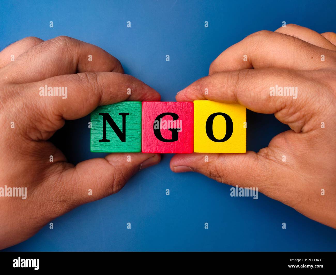 Hand holding colored cube with the word NGO on blue background Stock ...