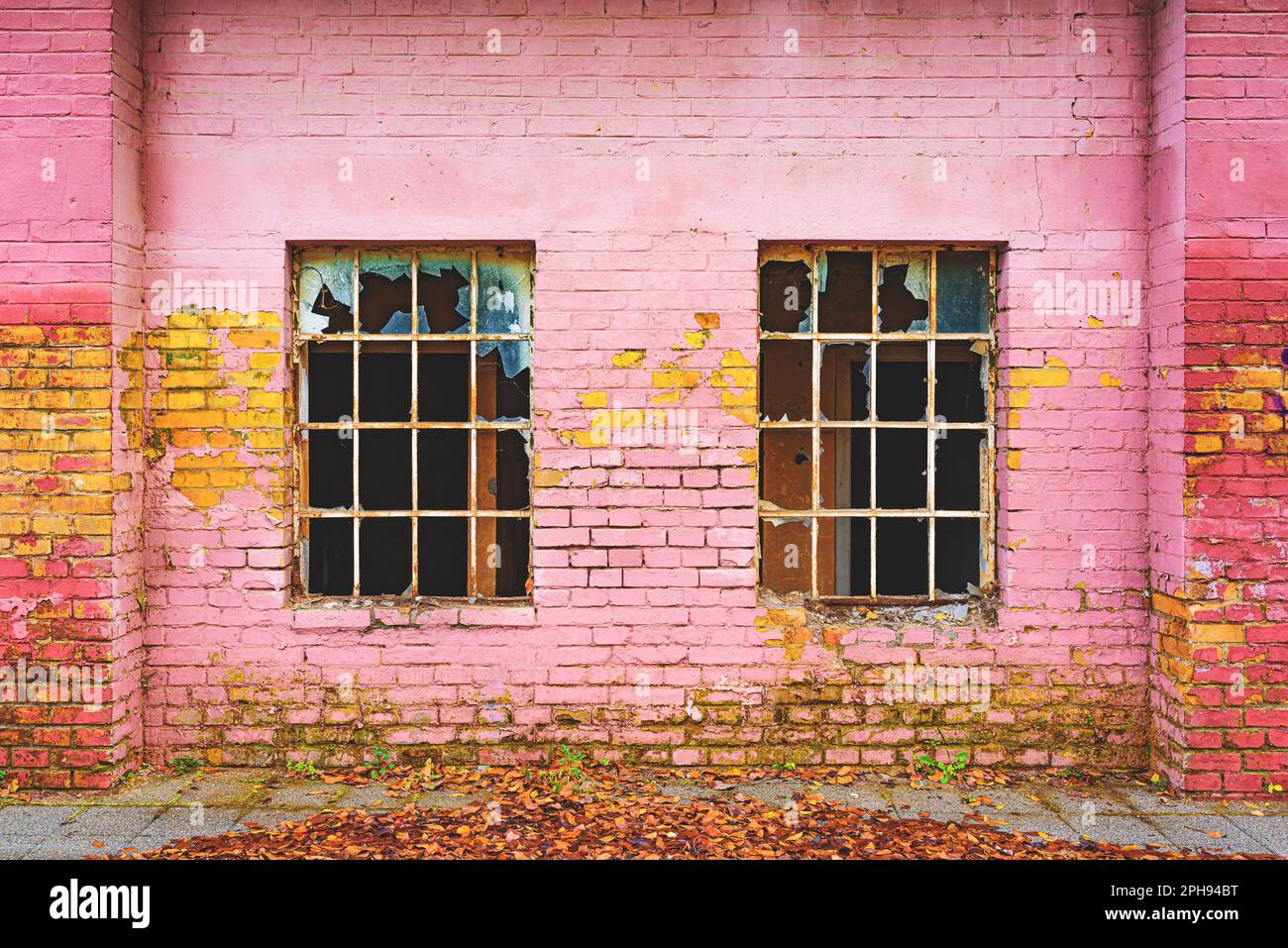 Old grid windows with broken glass on exterior wall of an old abandoned ...