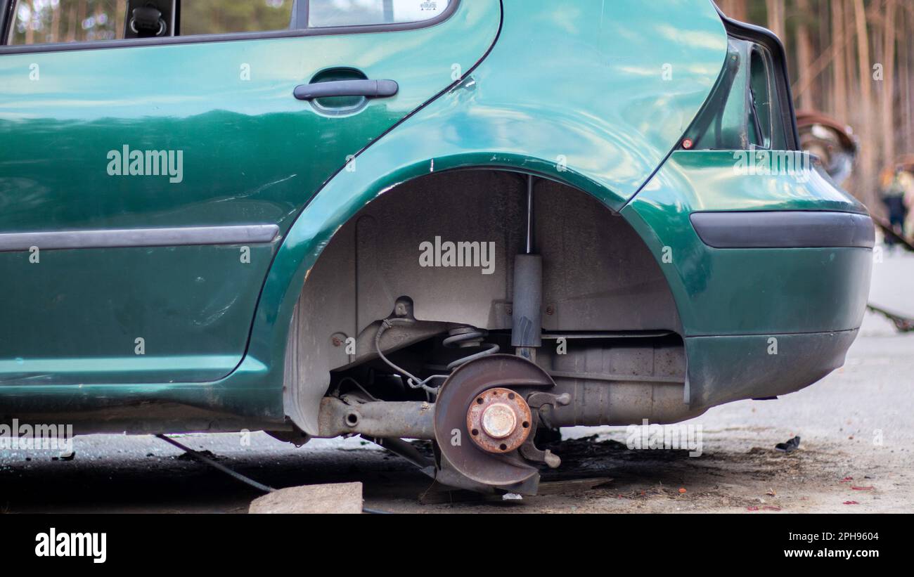 A car without a rear wheel on the side of the road. The rear hub of a ...