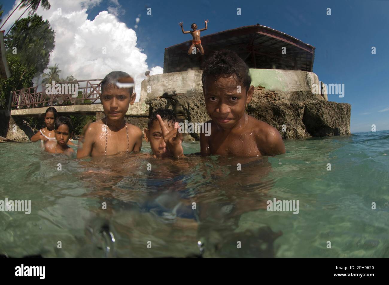Boys playing by jetty in shallow water, Ambon, Indonesia Stock Photo ...