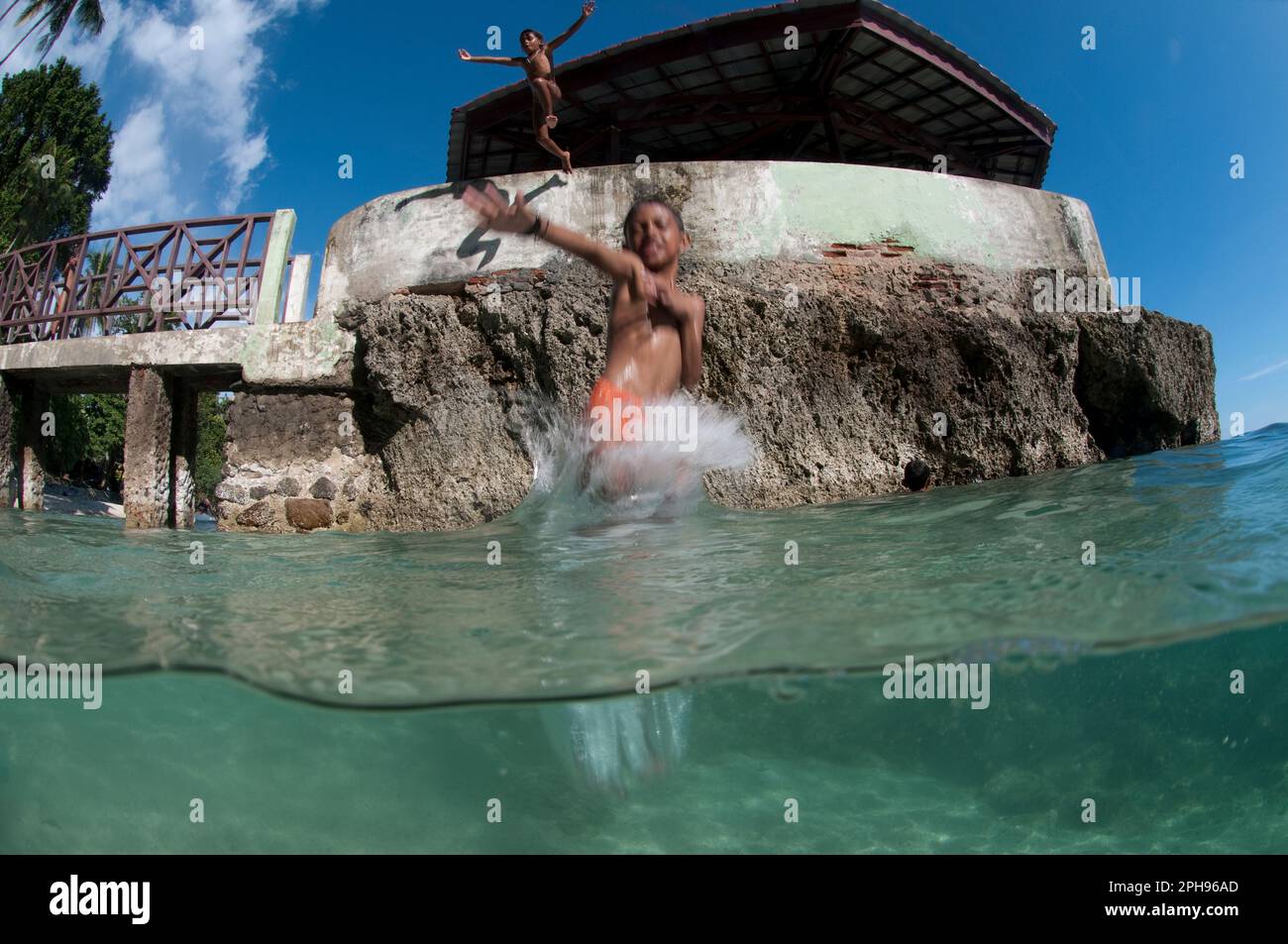 Boys playing by jetty in shallow water, Ambon, Indonesia Stock Photo ...