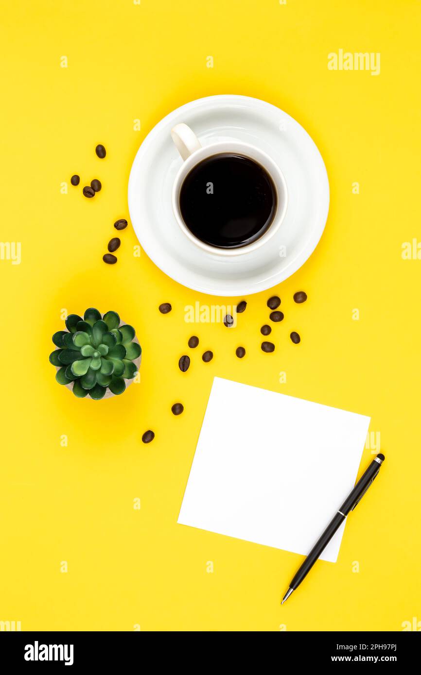 Cup of coffee, paper and coffee beans on a yellow background, flat lay ...
