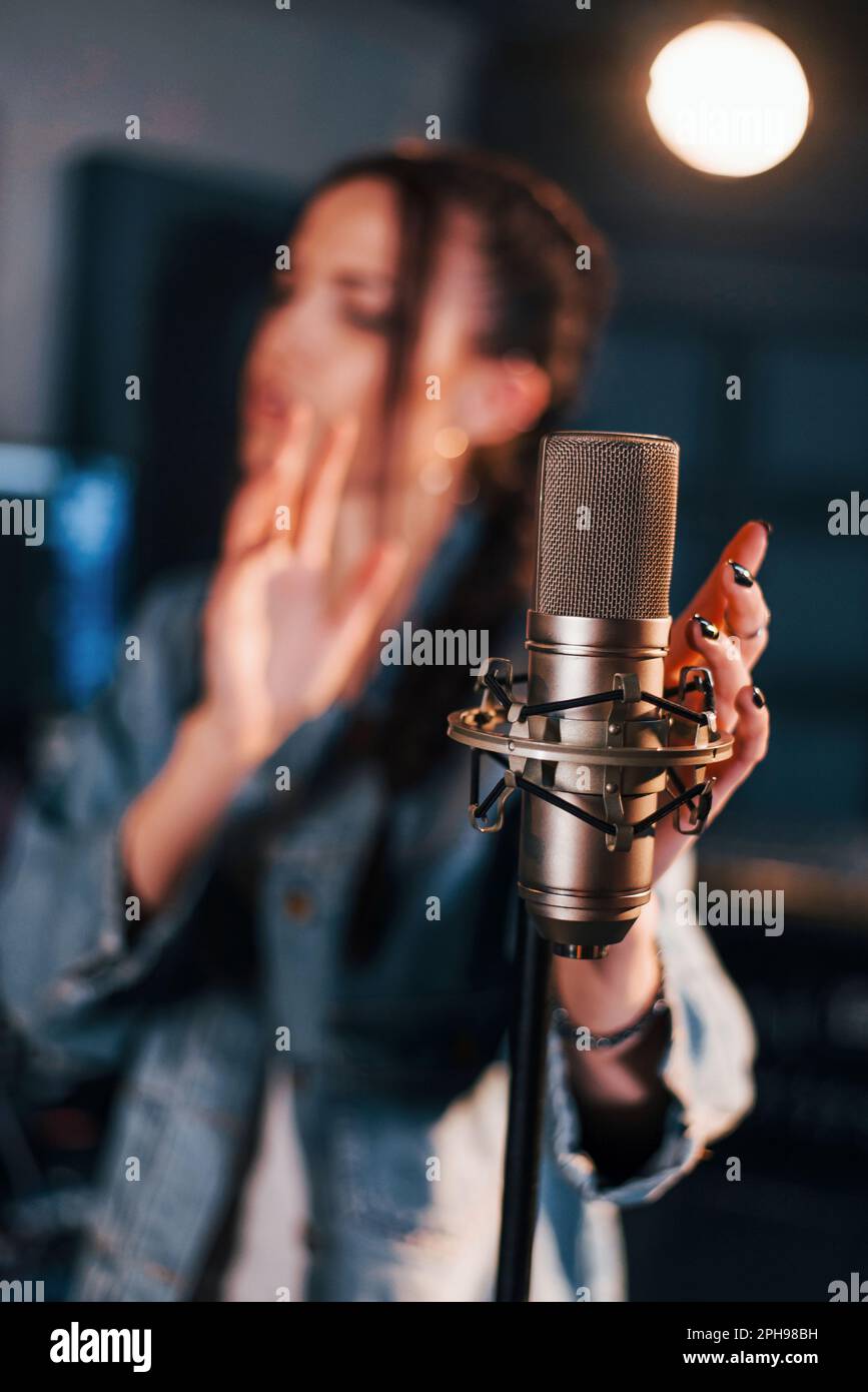 Close up view of microphone. Young beautiful female performer ...