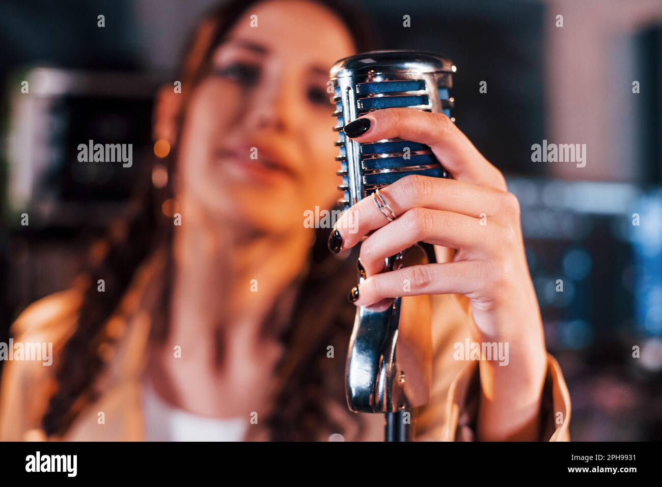 Close up view of microphone. Young beautiful female performer ...