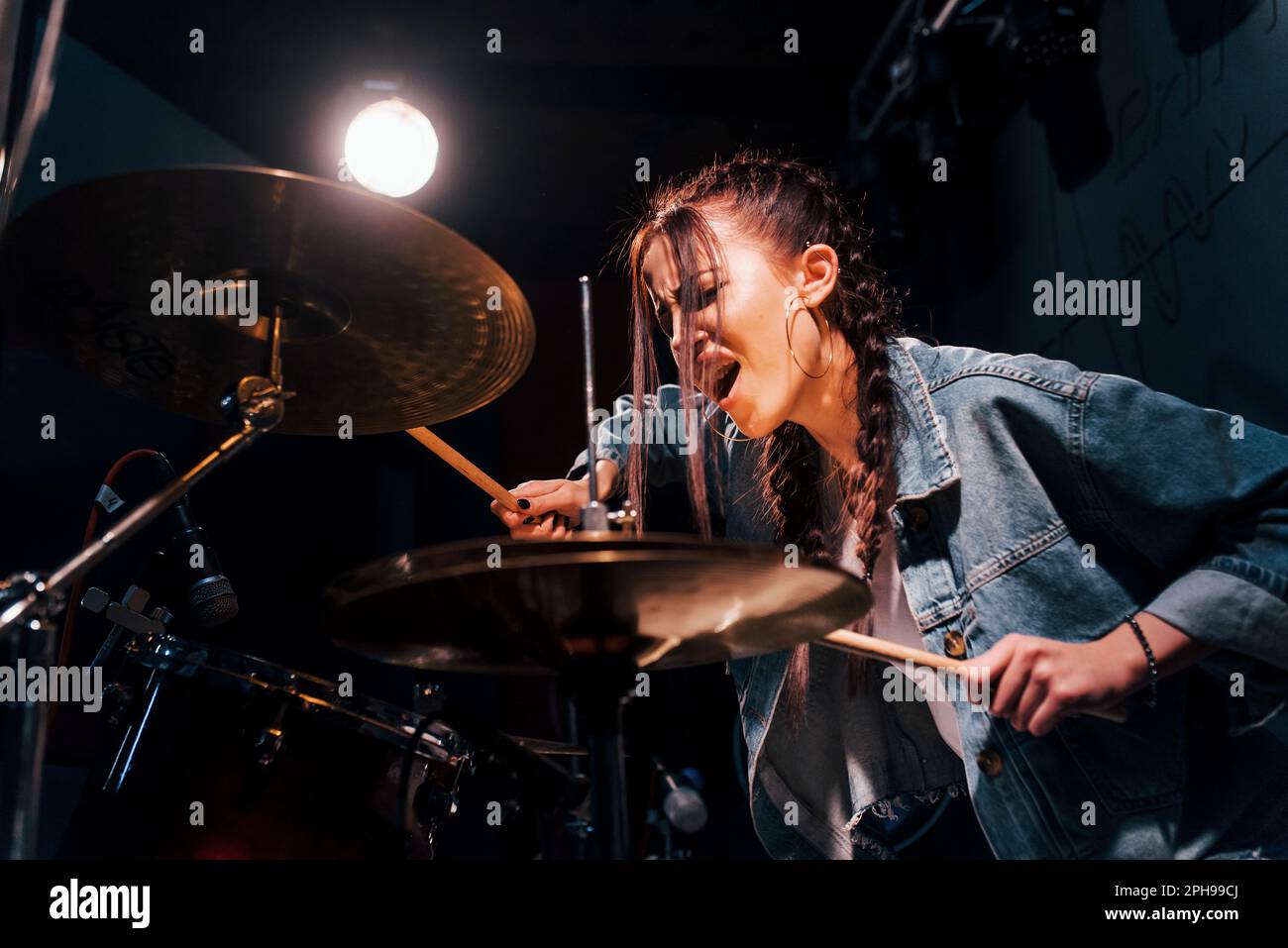 Plays drums. Young beautiful female performer rehearsing in a recording ...