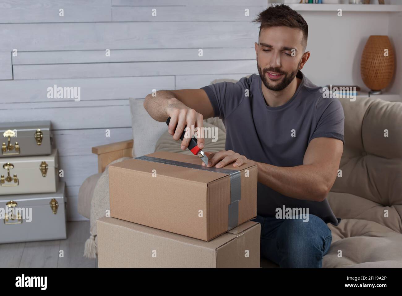 Man using utility knife to open parcel at home Stock Photo - Alamy