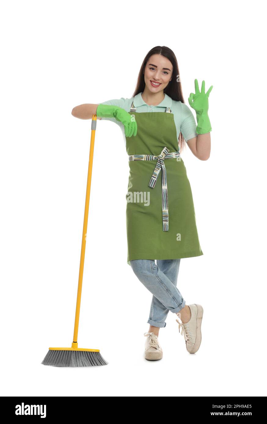 Beautiful young woman with broom showing OK gesture on white background ...