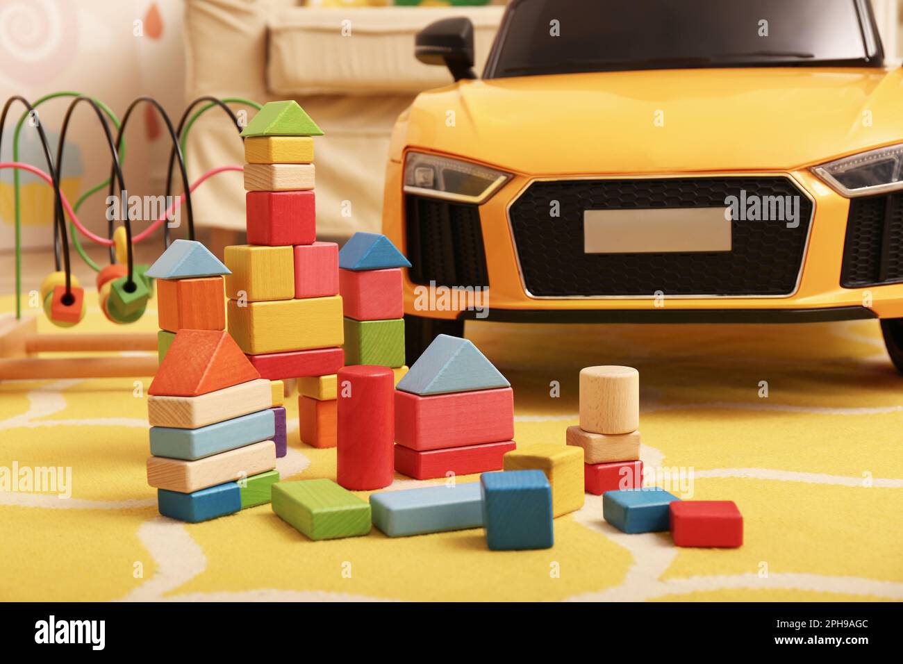 Colorful building blocks and child's electric car on floor in playroom ...