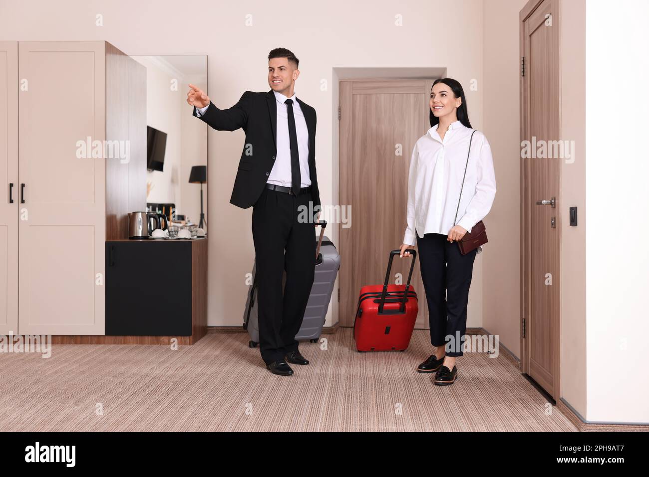 Happy businesspeople with suitcases walking into hotel room Stock Photo ...