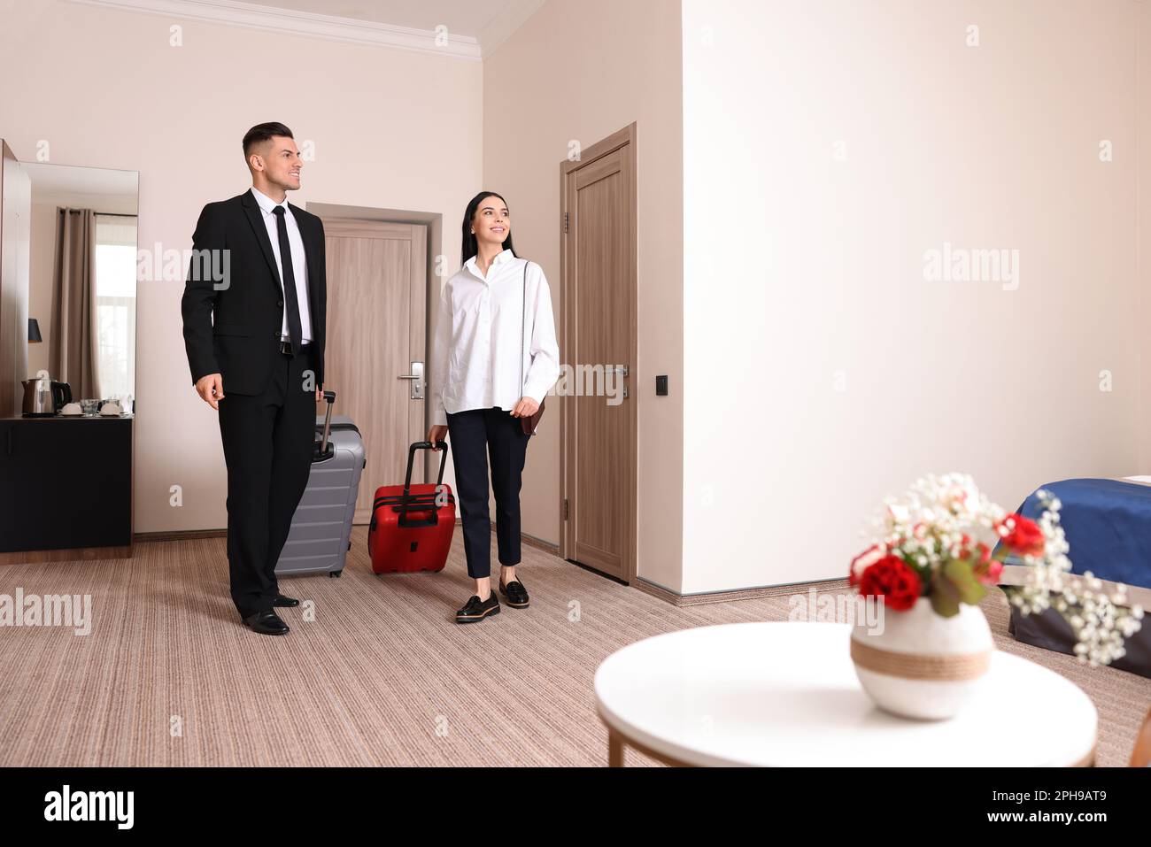 Happy businesspeople with suitcases walking into hotel room Stock Photo ...