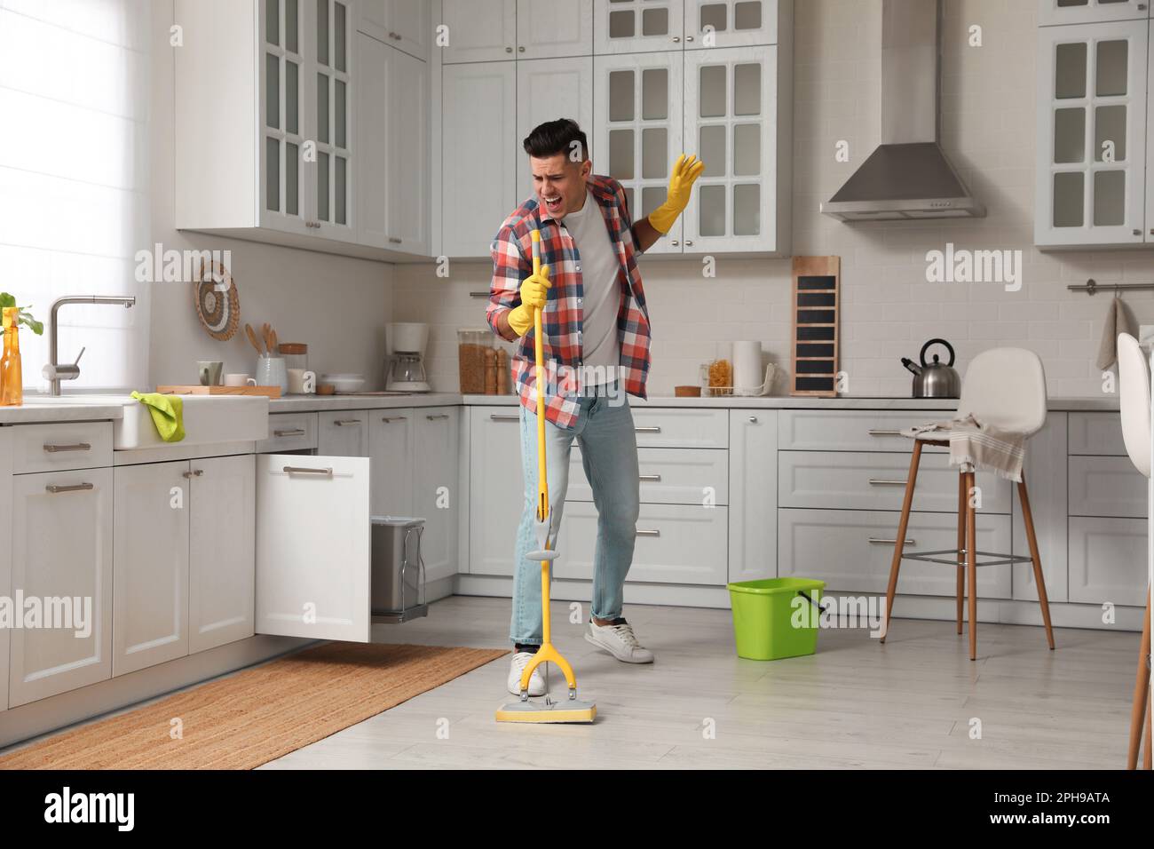 Man with mop singing while cleaning at home Stock Photo - Alamy