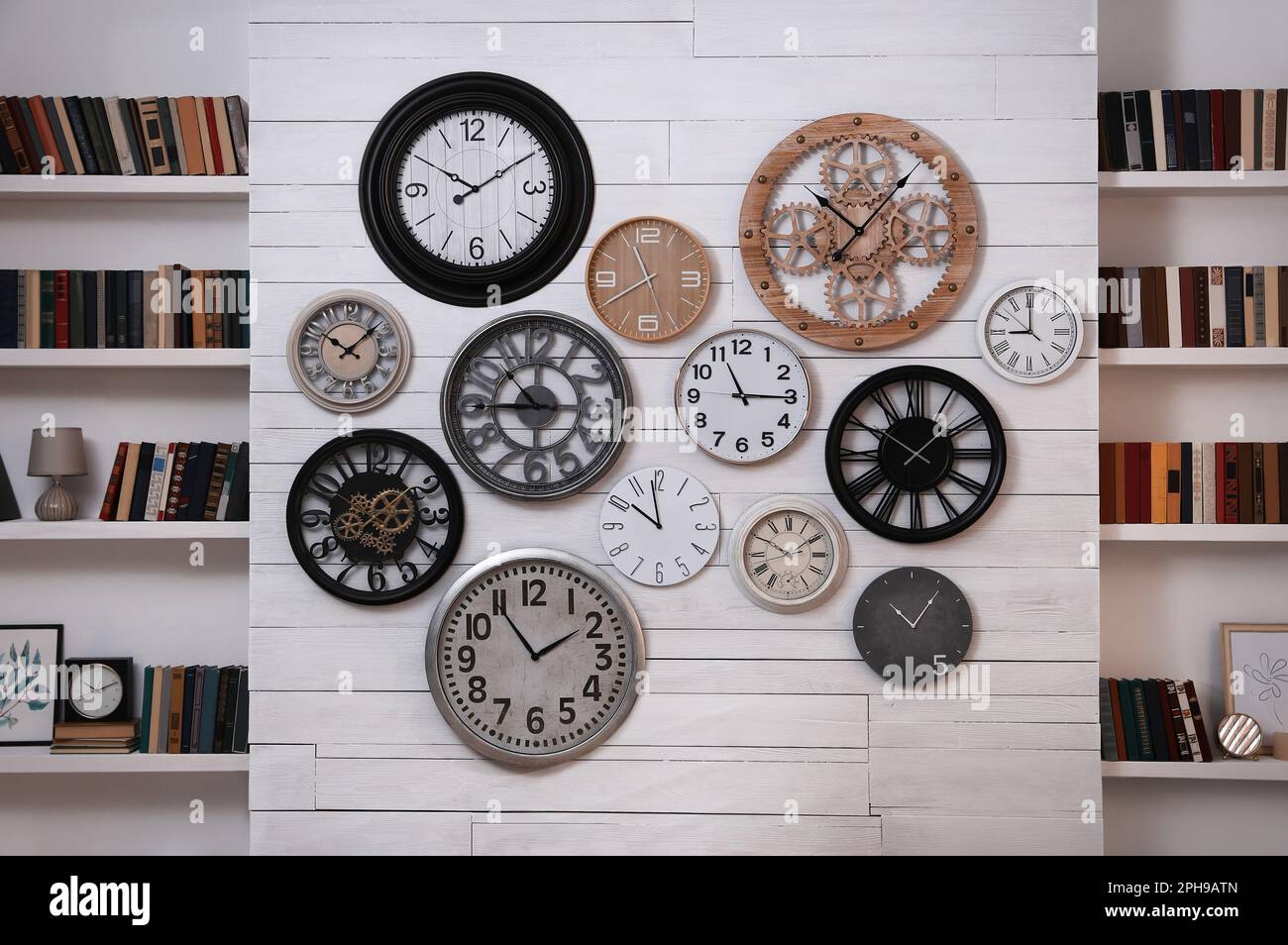 Collection of different clocks between bookshelves in room. Interior ...