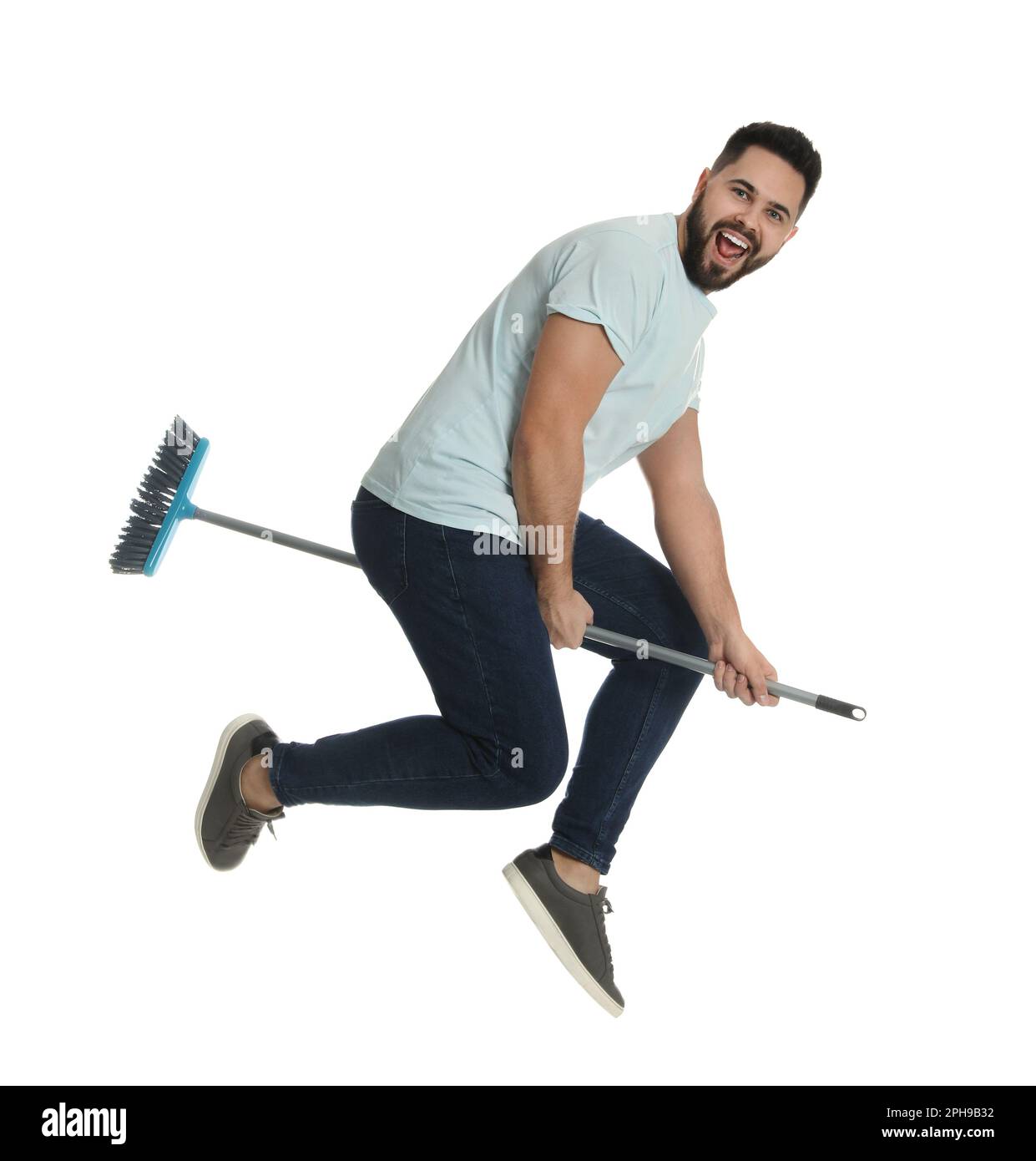 Young man with broom jumping on white background Stock Photo - Alamy
